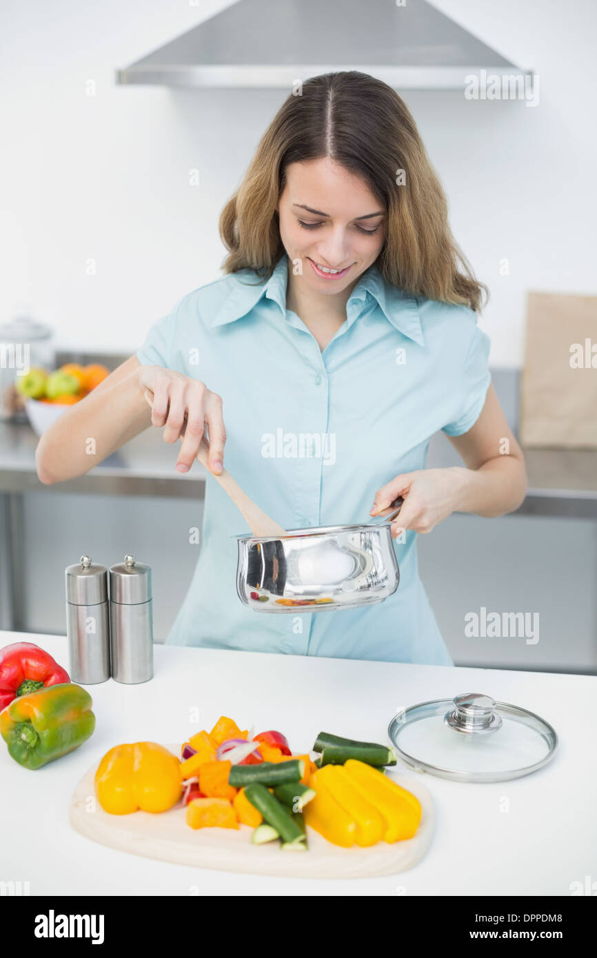 Content woman cooking while standing in kitchen Stock Photo - Alamy