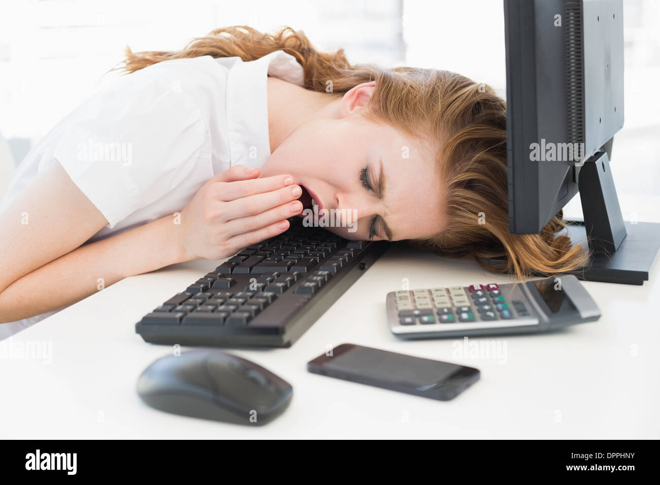 Asleep businesswoman yawning on keyboard at office Stock Photo - Alamy
