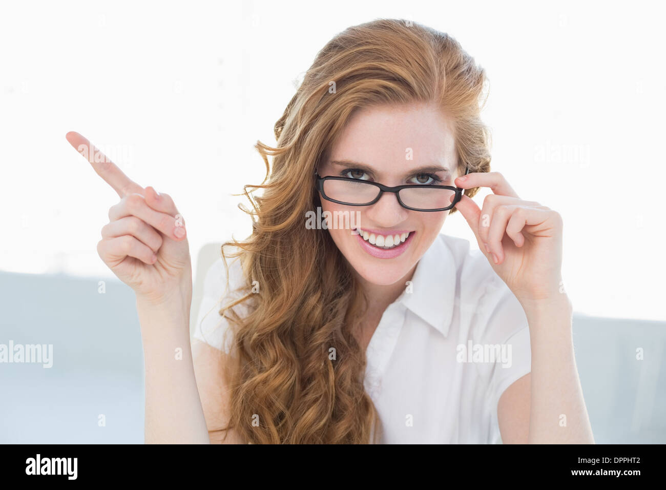 Cheerful businesswoman pointing to side in office Stock Photo - Alamy