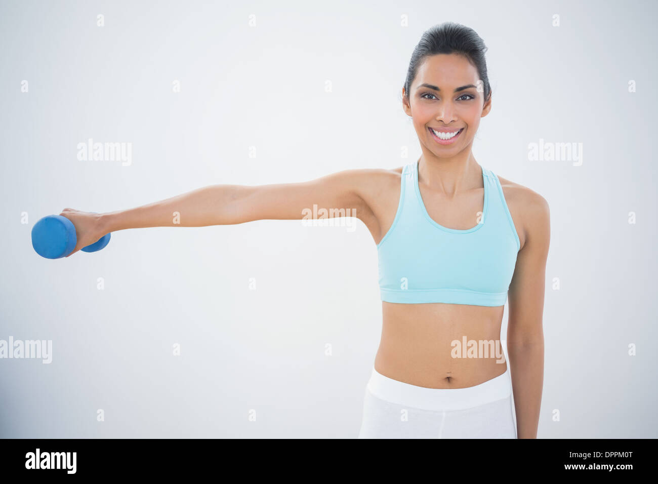Slender dark haired woman lifting blue dumbbell Stock Photo - Alamy