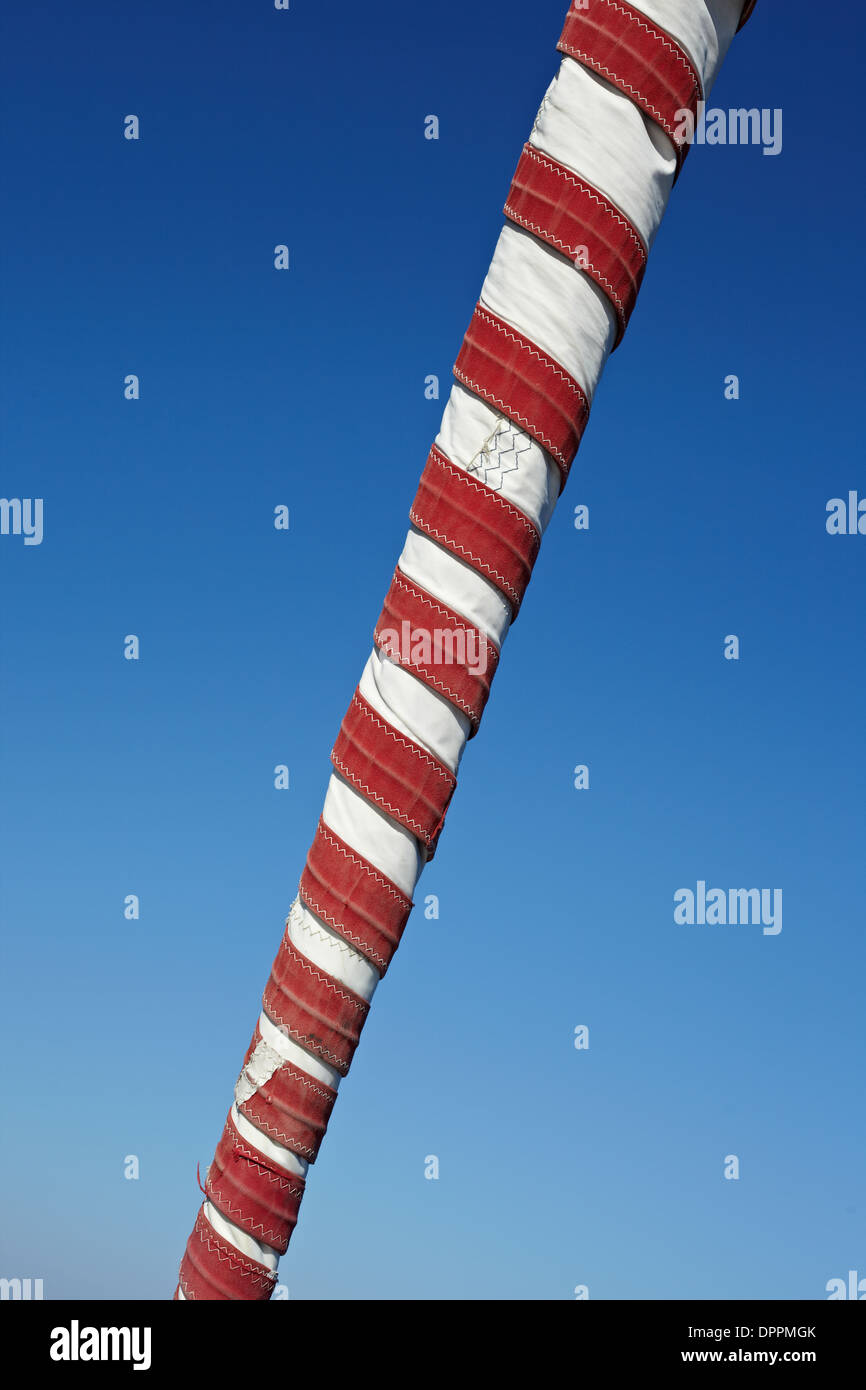 rolled up sail in front of blue sky Stock Photo - Alamy
