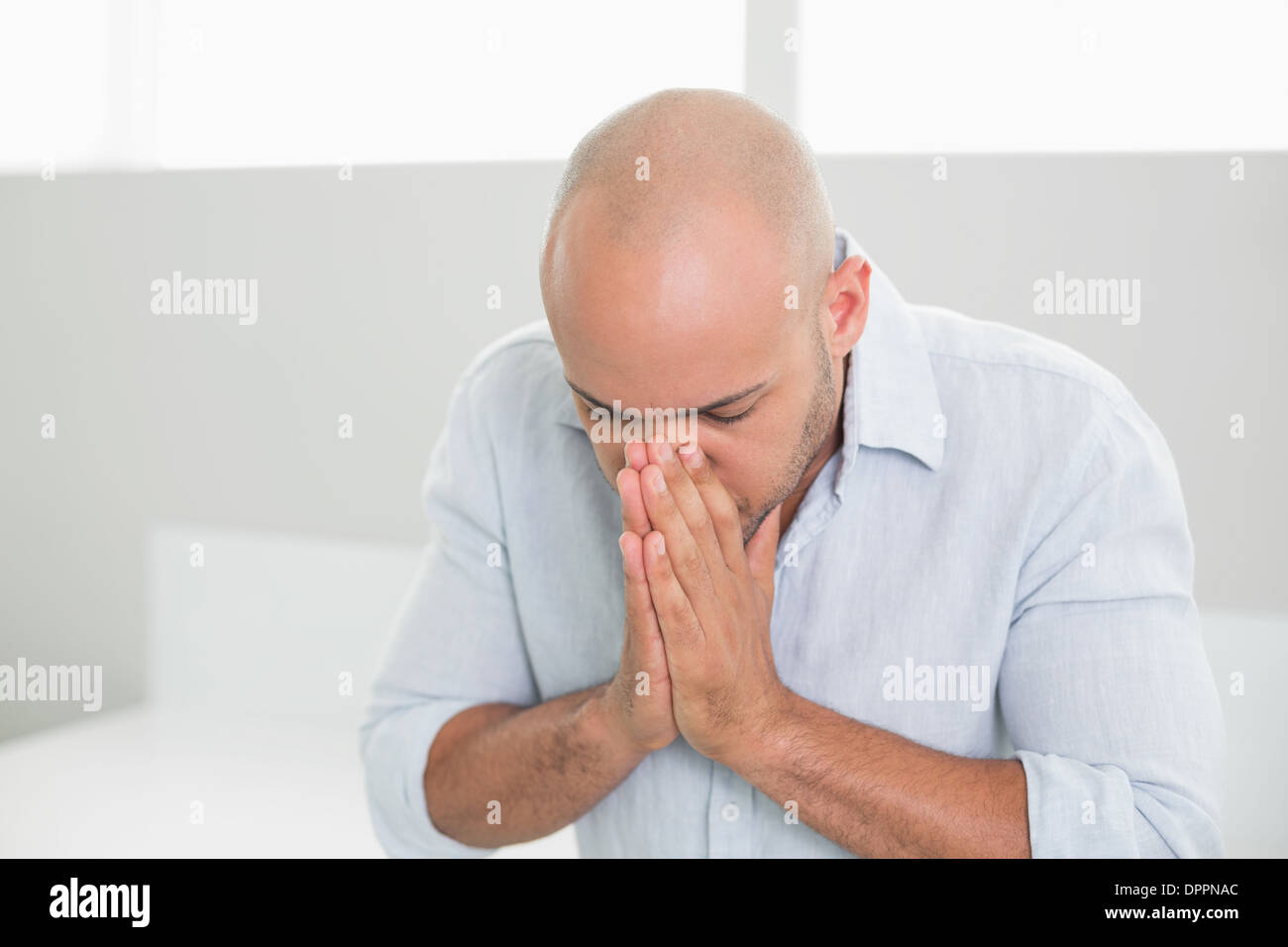 Sad casual man with hands to his face at home Stock Photo - Alamy