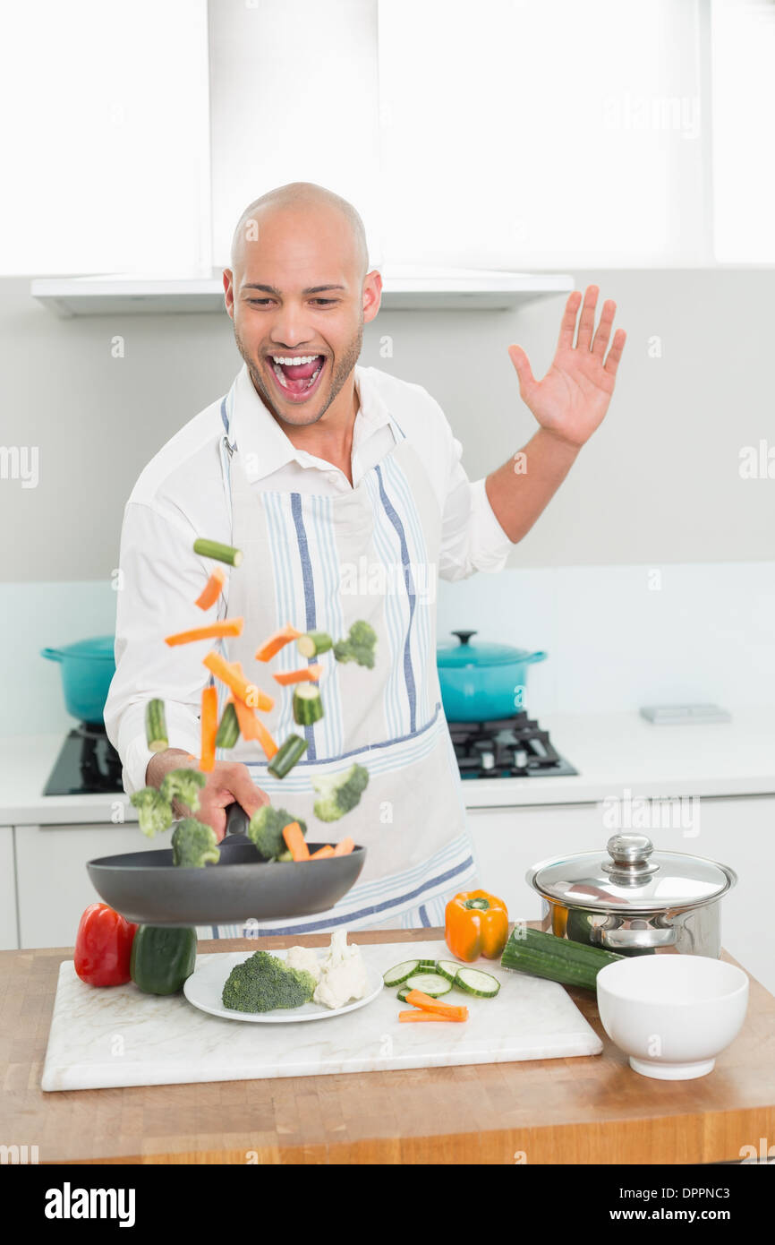 Cheerful man tossing vegetables in kitchen Stock Photo - Alamy