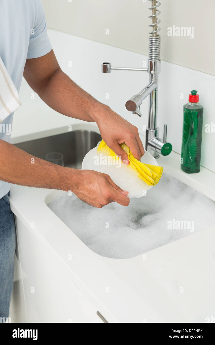 Mid section of man doing the dishes at kitchen sink Stock Photo - Alamy
