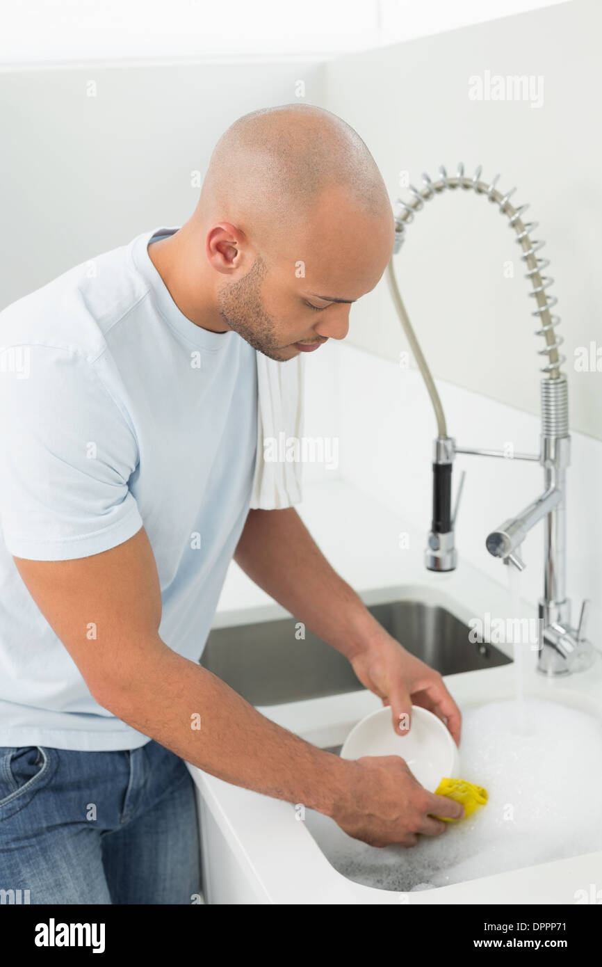 Young man doing the dishes at kitchen sink Stock Photo - Alamy