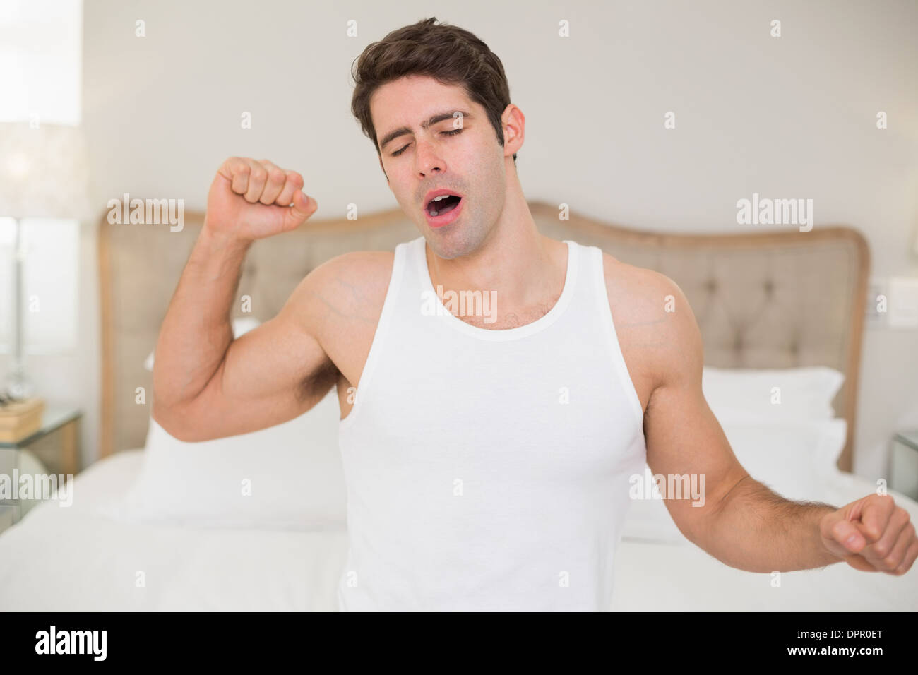 Young man waking up in bed and stretching arms Stock Photo - Alamy