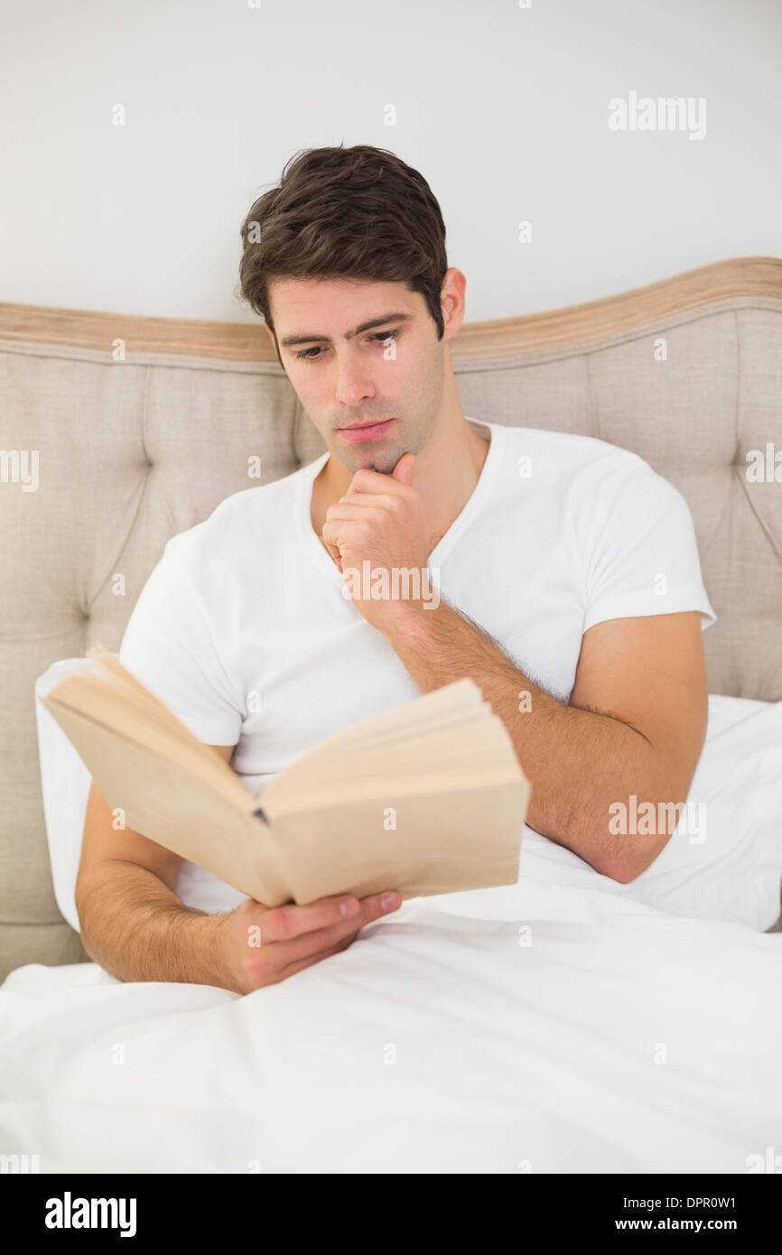 Relaxed man reading book in bed Stock Photo - Alamy