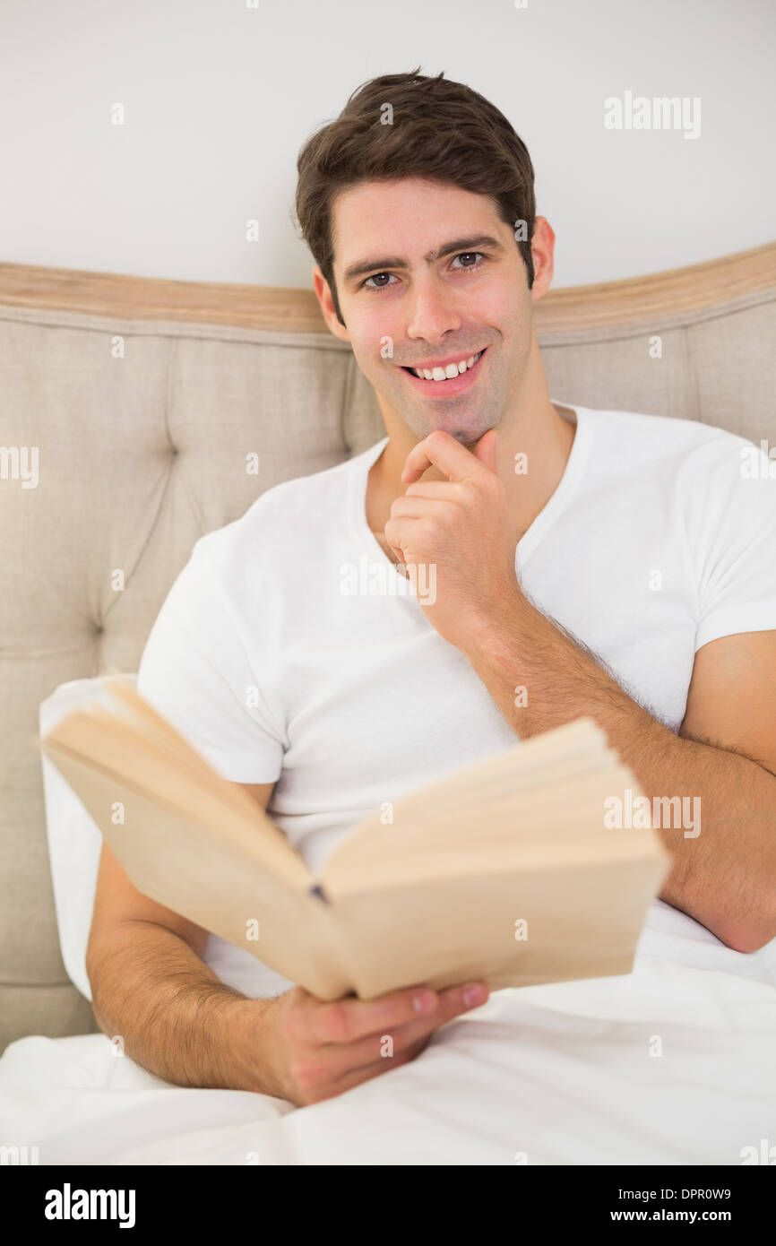 Portrait of relaxed young man reading book in bed Stock Photo - Alamy