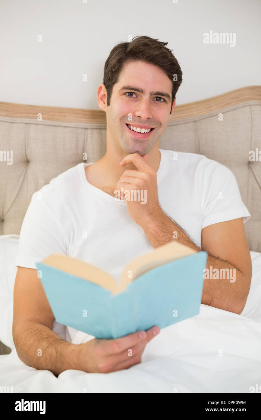 Portrait of relaxed young man reading book in bed Stock Photo - Alamy