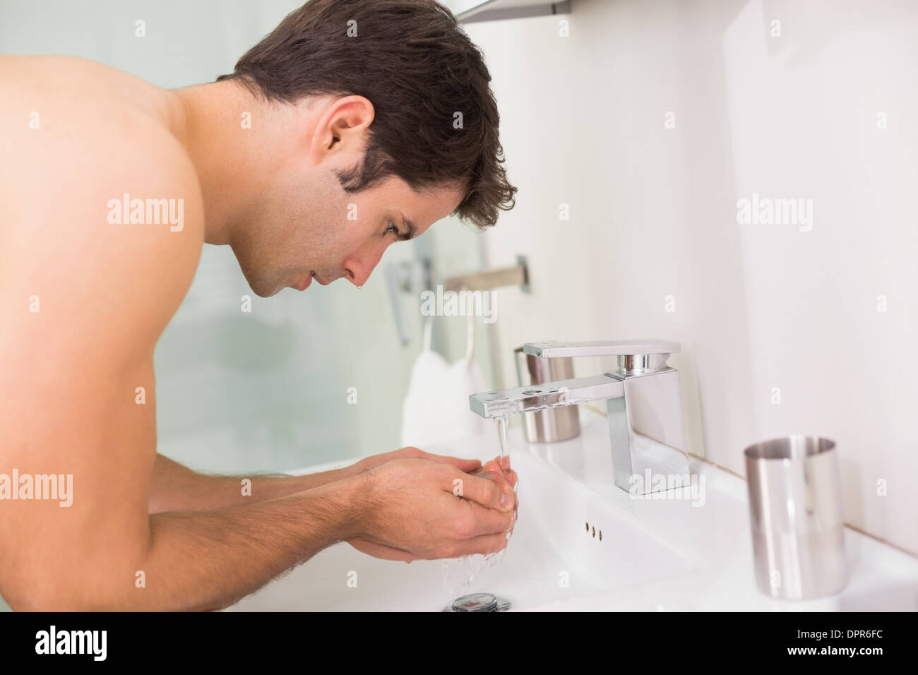 Shirtless young man washing face in bathroom Stock Photo - Alamy