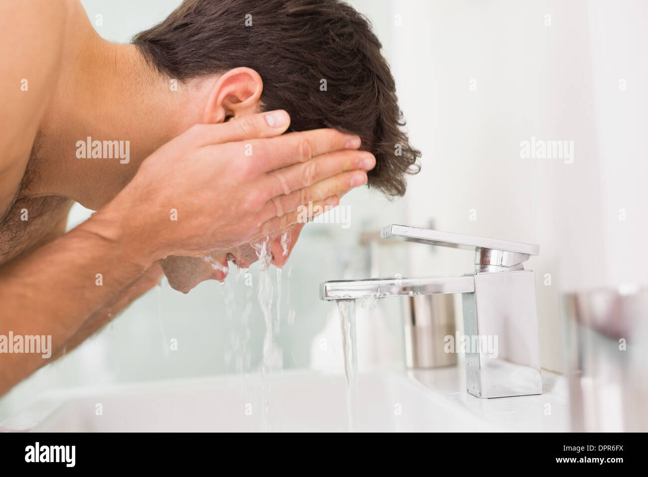 Shirtless young man washing face in bathroom Stock Photo - Alamy
