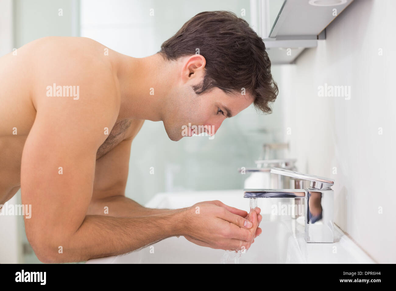 Shirtless young man washing face in bathroom Stock Photo - Alamy