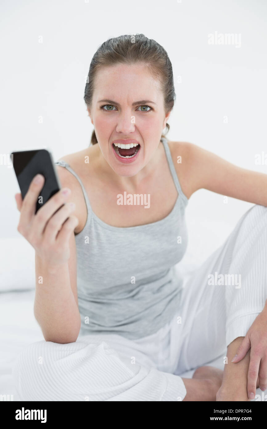 Portrait of an angry woman shouting with mobile phone in hand Stock ...