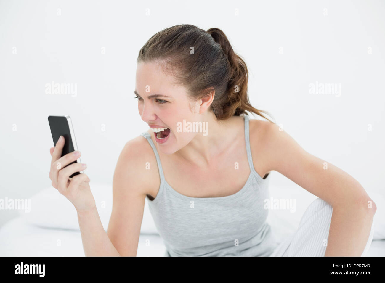 Woman shouting into mobile phone in bed Stock Photo - Alamy