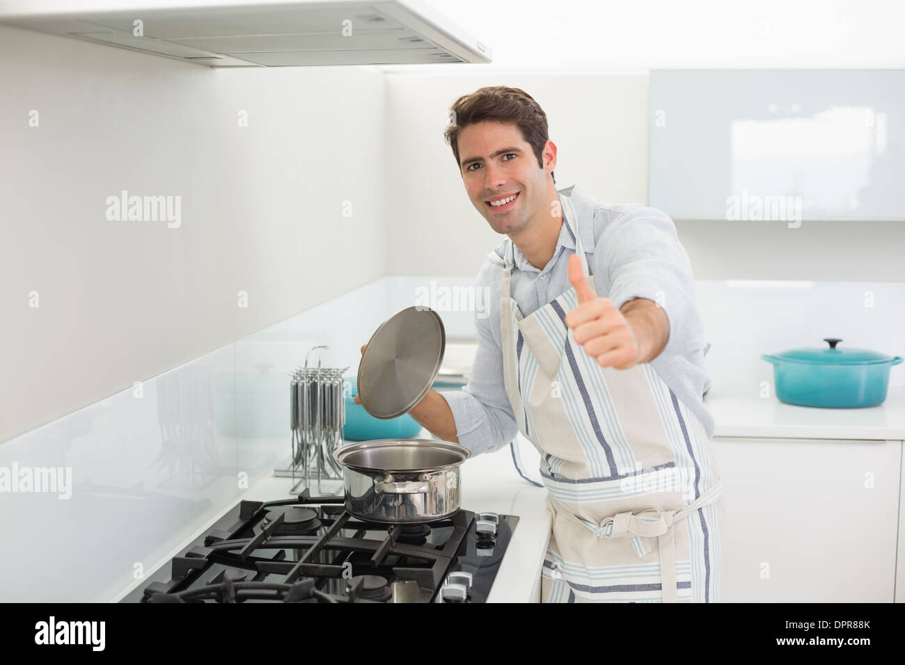 Smiling young man gesturing thumbs up in kitchen Stock Photo - Alamy