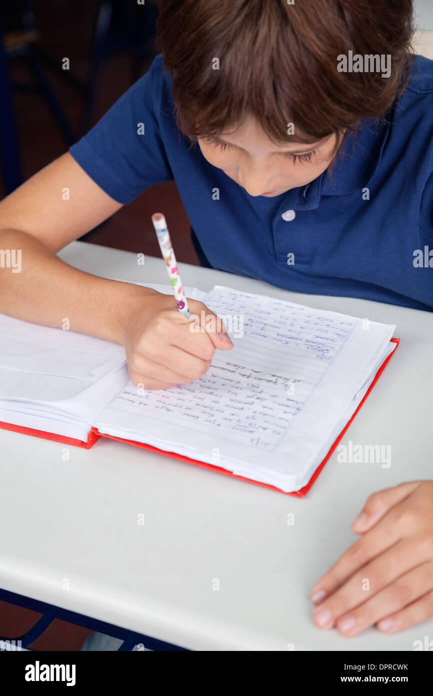 Little Schoolboy Reading Book At Desk Stock Photo - Alamy