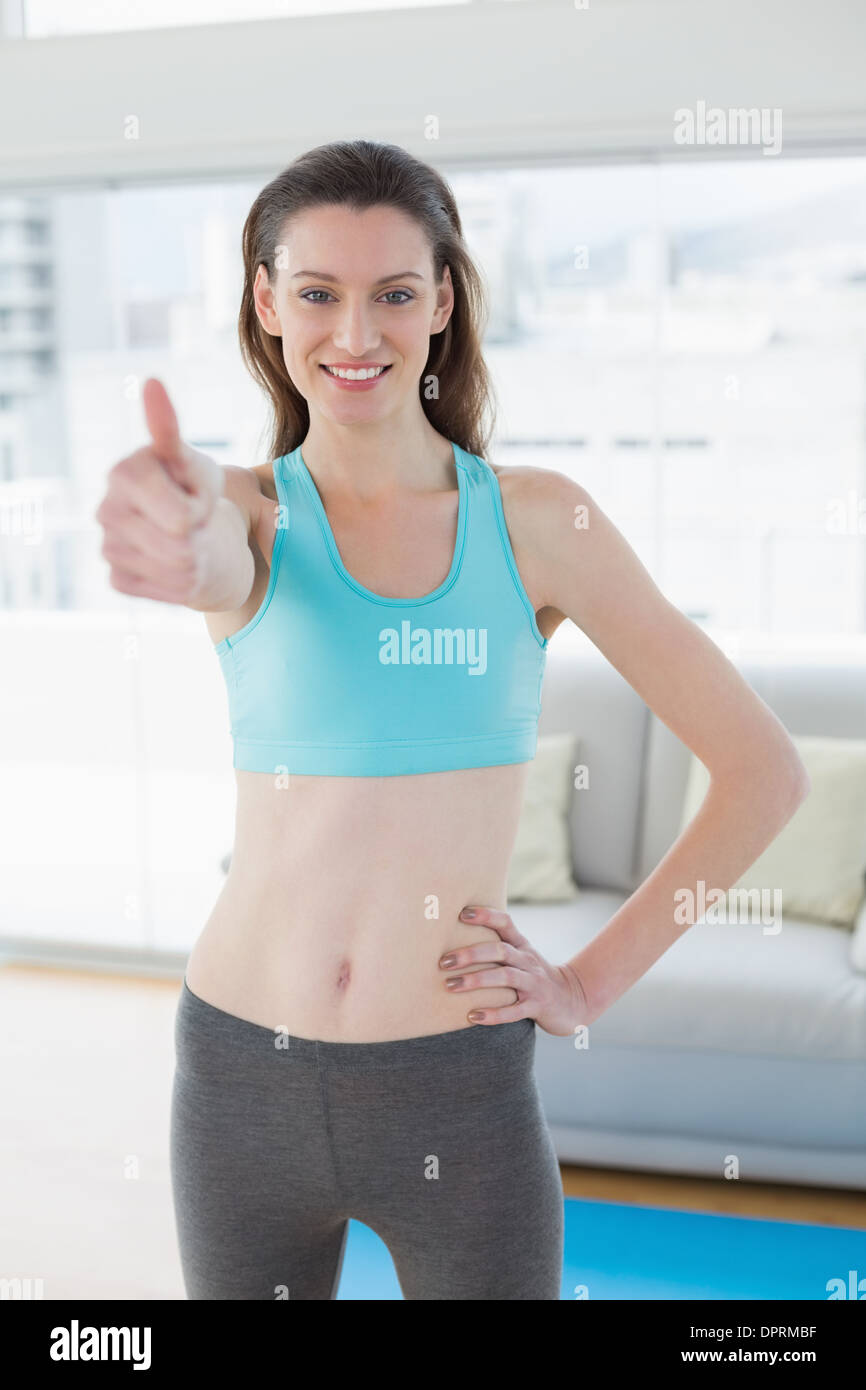 Toned woman gesturing thumbs up in fitness studio Stock Photo - Alamy