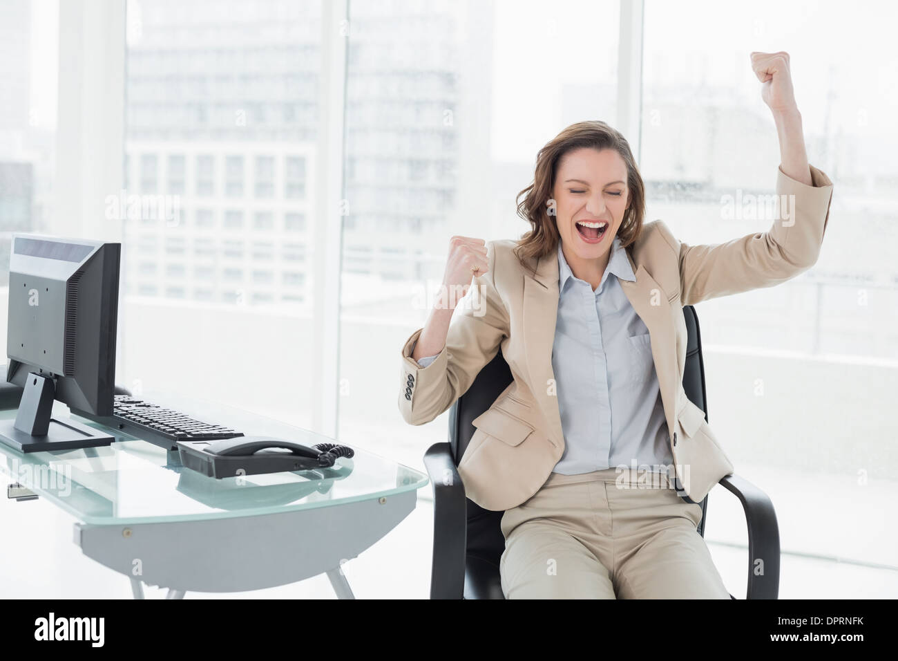 Businesswoman cheering with hands raised in office Stock Photo - Alamy