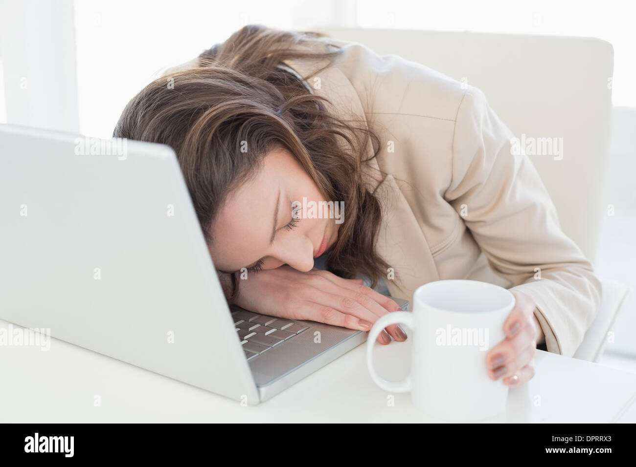 Businesswoman resting head on desk by coffee cup hi-res stock ...