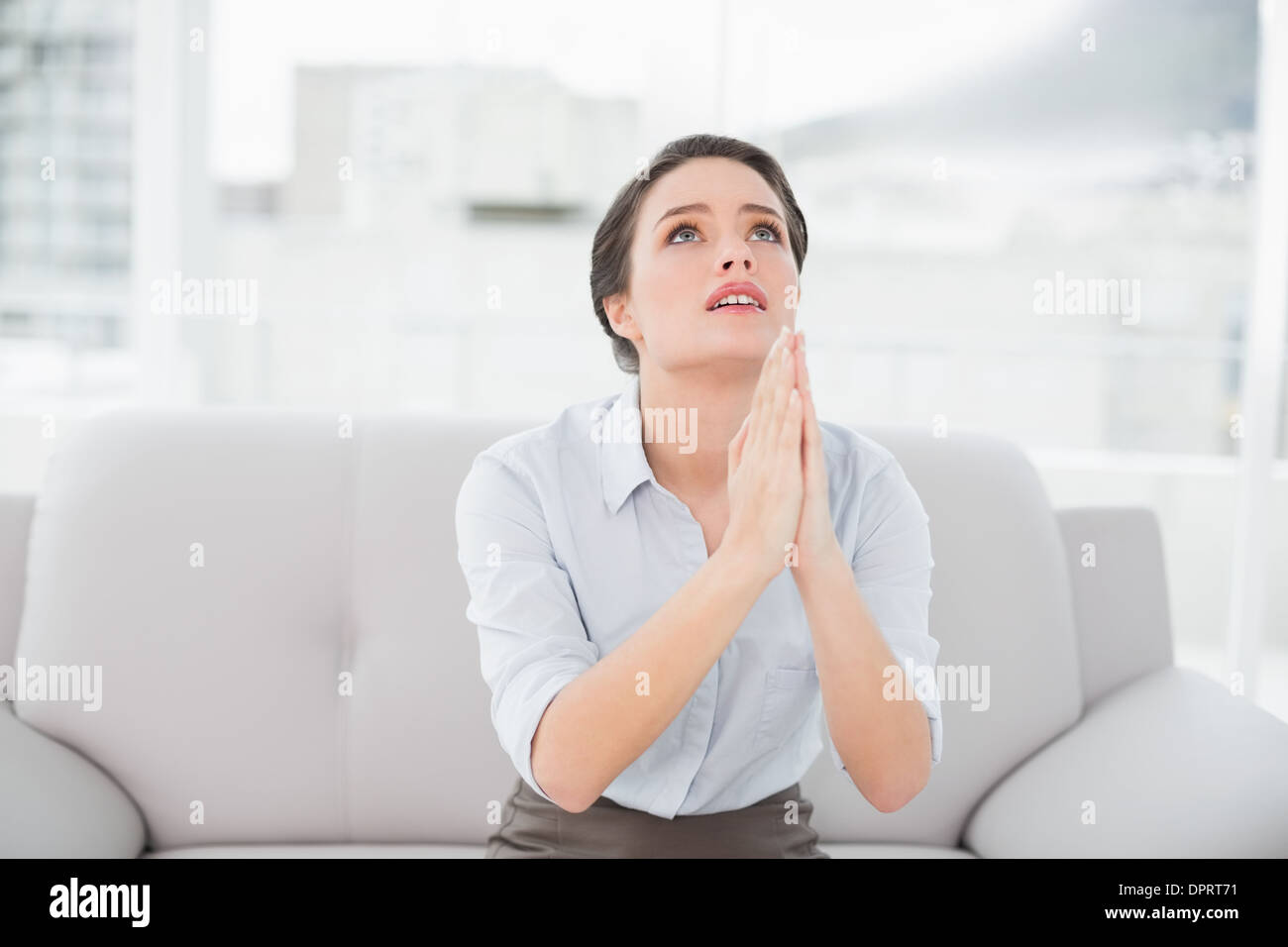 Worried well dressed woman with joined hands looking up Stock Photo - Alamy