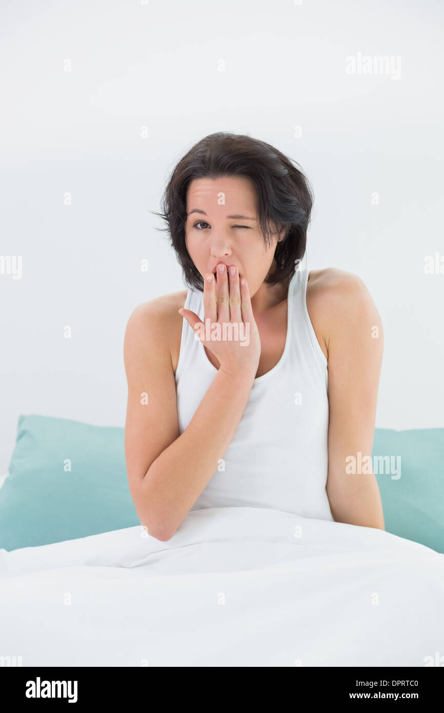 Portrait of a young woman yawning in bed Stock Photo - Alamy