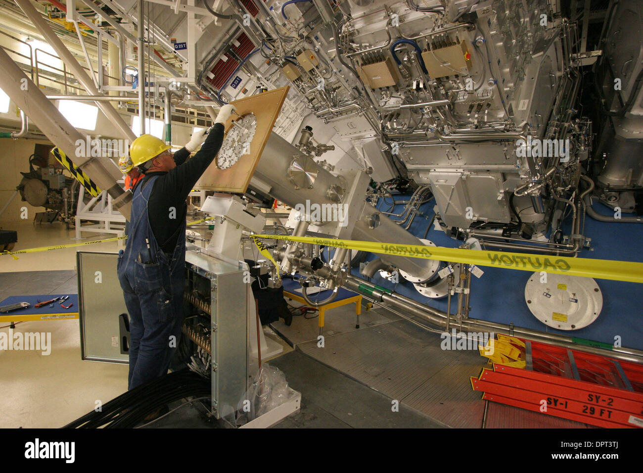 A workman installs a diagnostic lens on the target chamber at NIF at ...