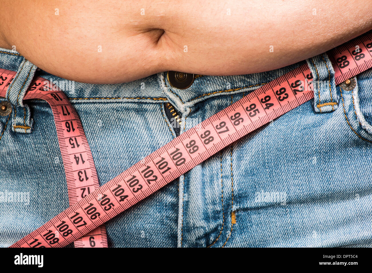 Woman showing fat belly. Pink tape measure Stock Photo - Alamy