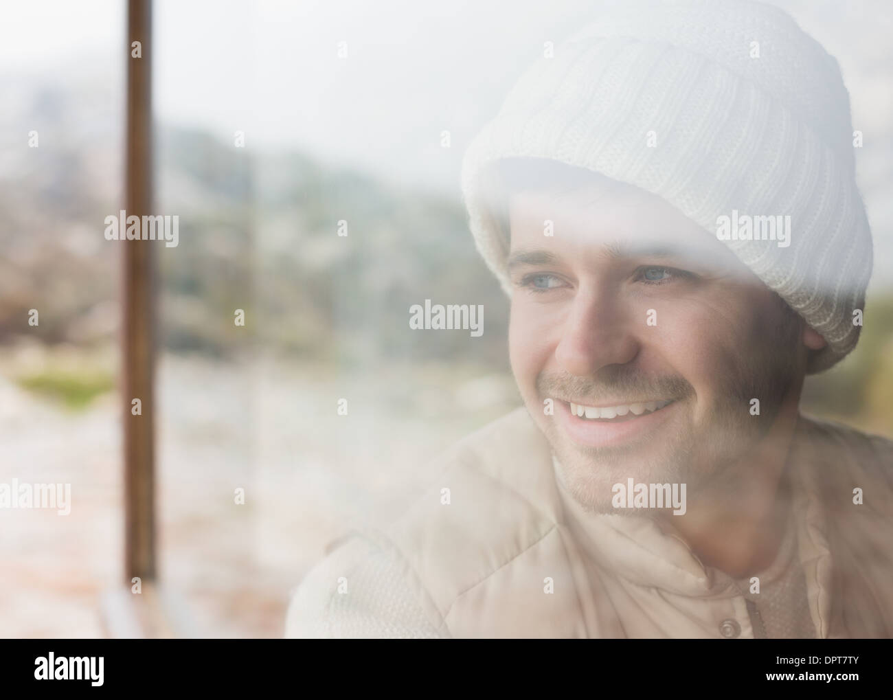 Thoughtful smiling man looking out through window Stock Photo - Alamy