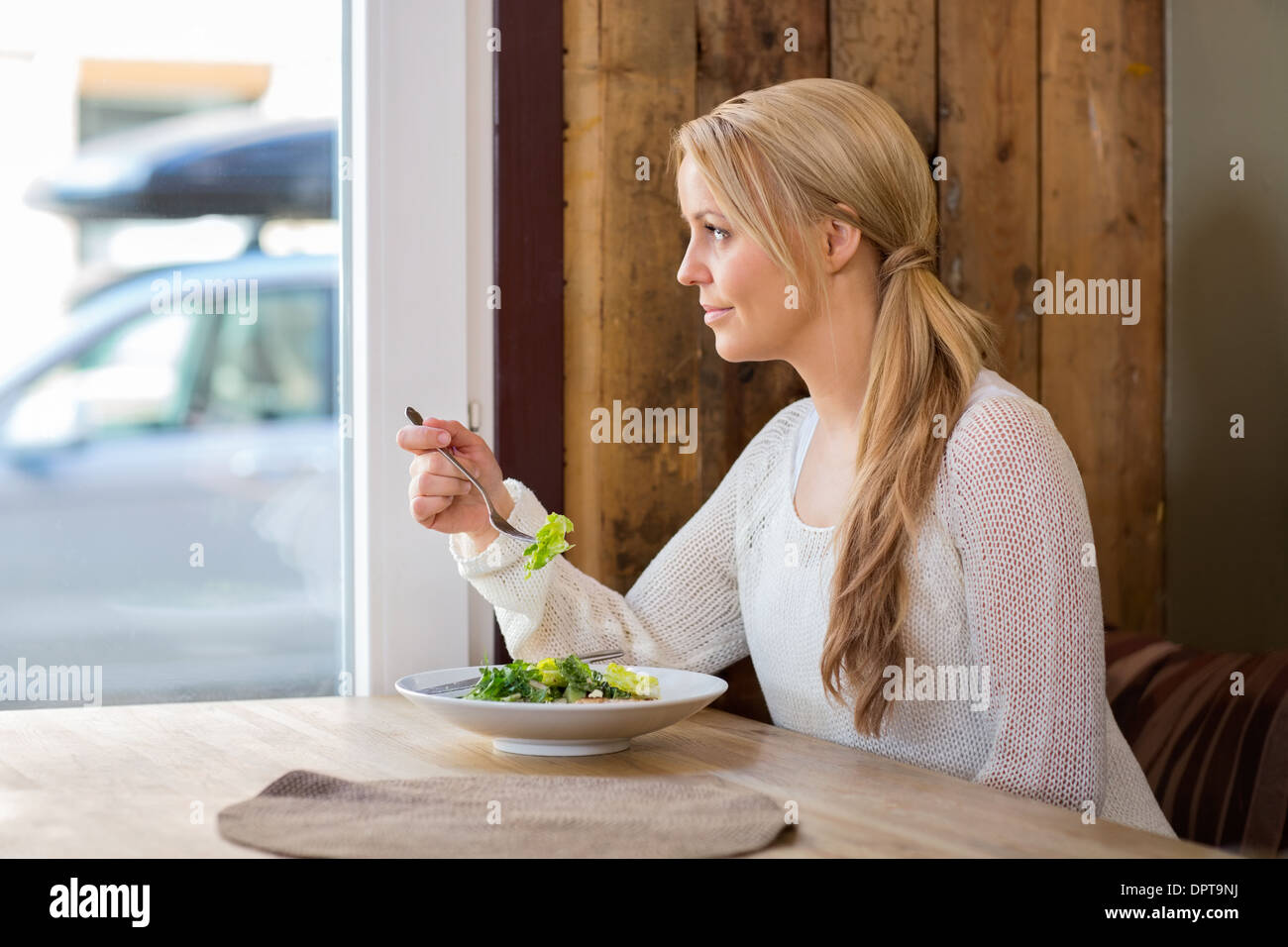 Woman Looking Through Window While Eating Salad Stock Photo - Alamy