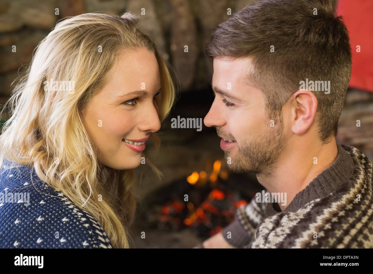 Romantic couple smiling in front of fireplace Stock Photo - Alamy