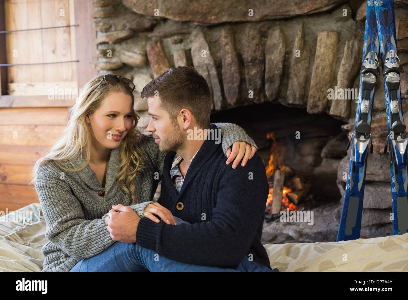 Romantic couple in front of lit fireplace Stock Photo - Alamy