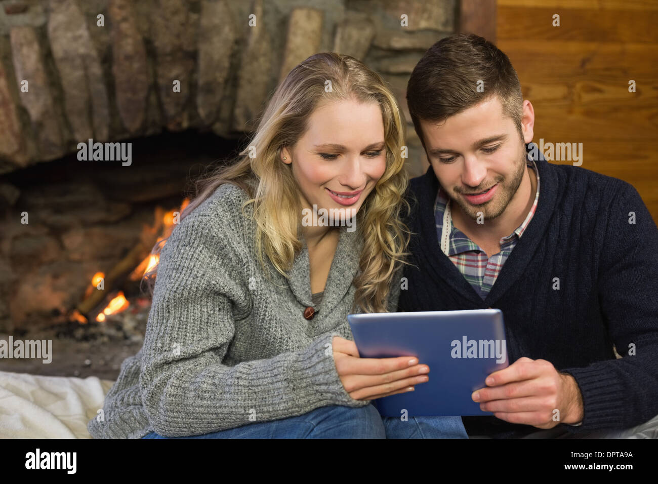 Couple using tablet PC in front of lit fireplace Stock Photo - Alamy