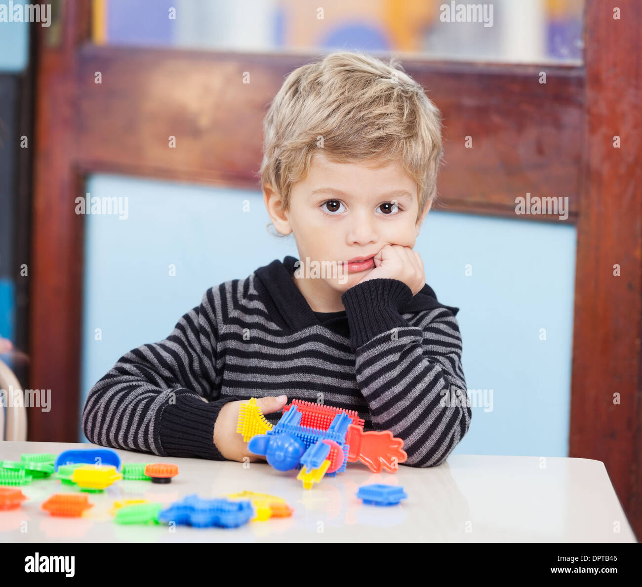 Unhappy Boy With Blocks In Classroom Stock Photo - Alamy