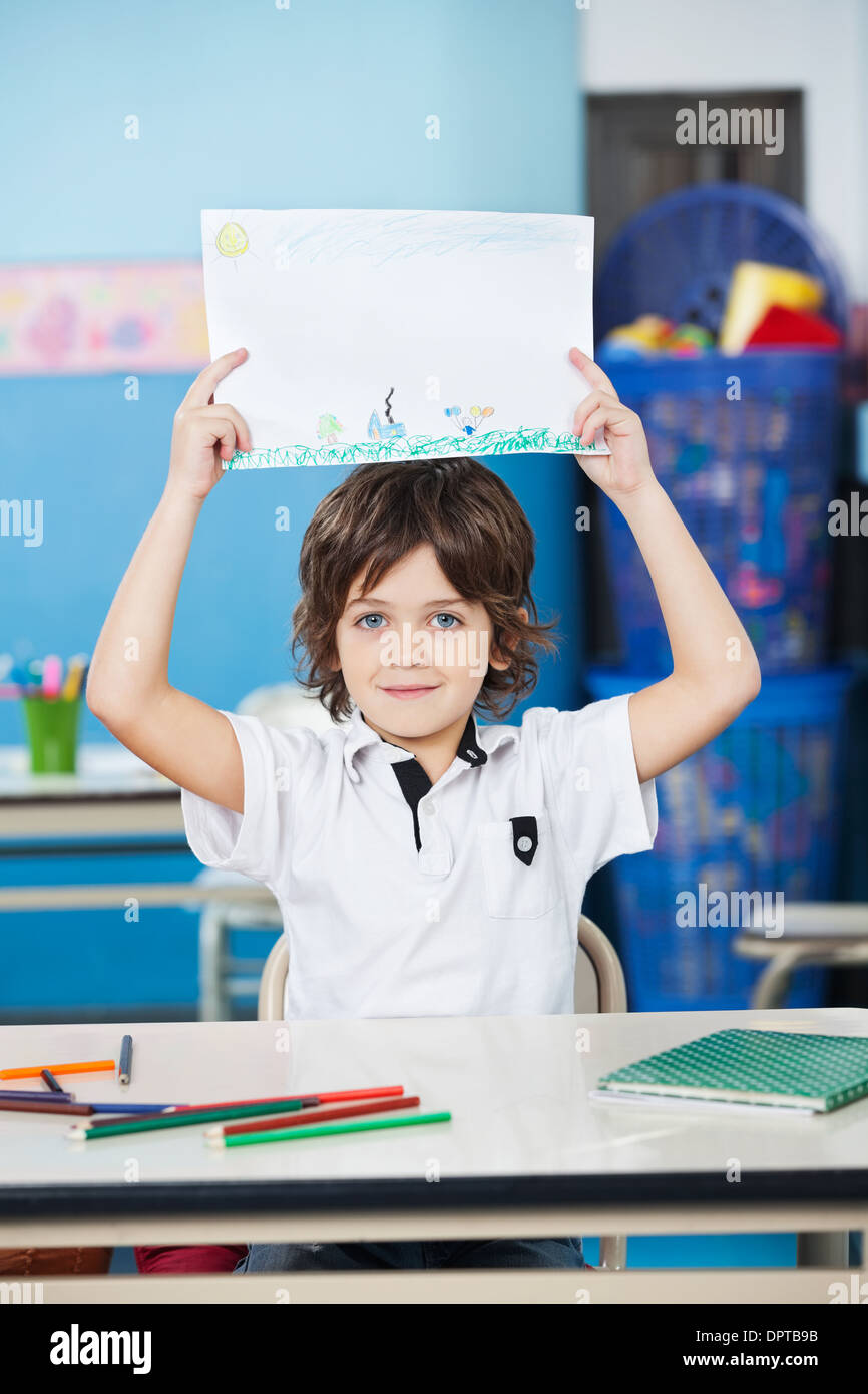 Boy Holding Drawing Paper At Desk In Kindergarten Stock Photo - Alamy