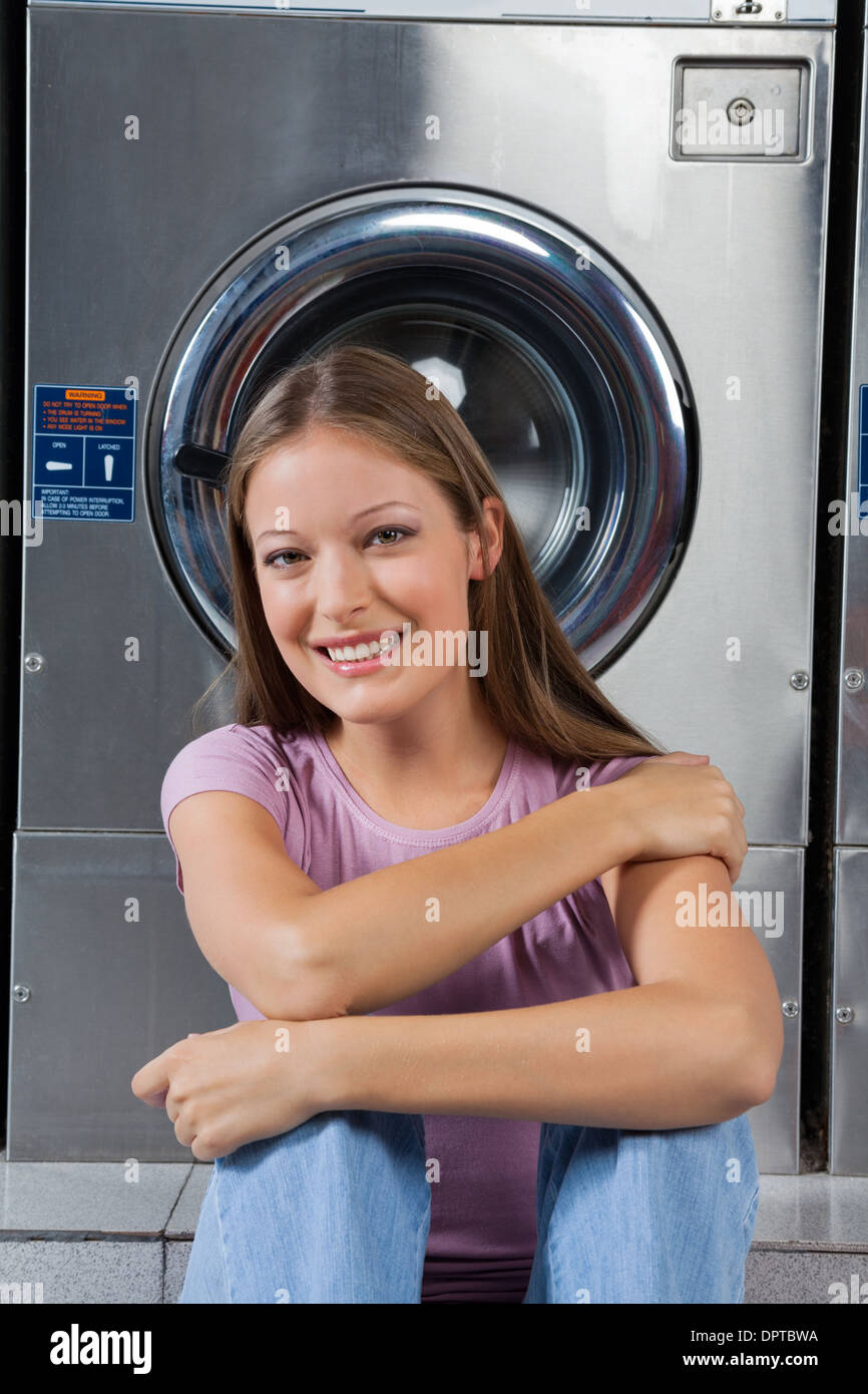 Beautiful Woman Sitting Against Washing Machine Stock Photo - Alamy