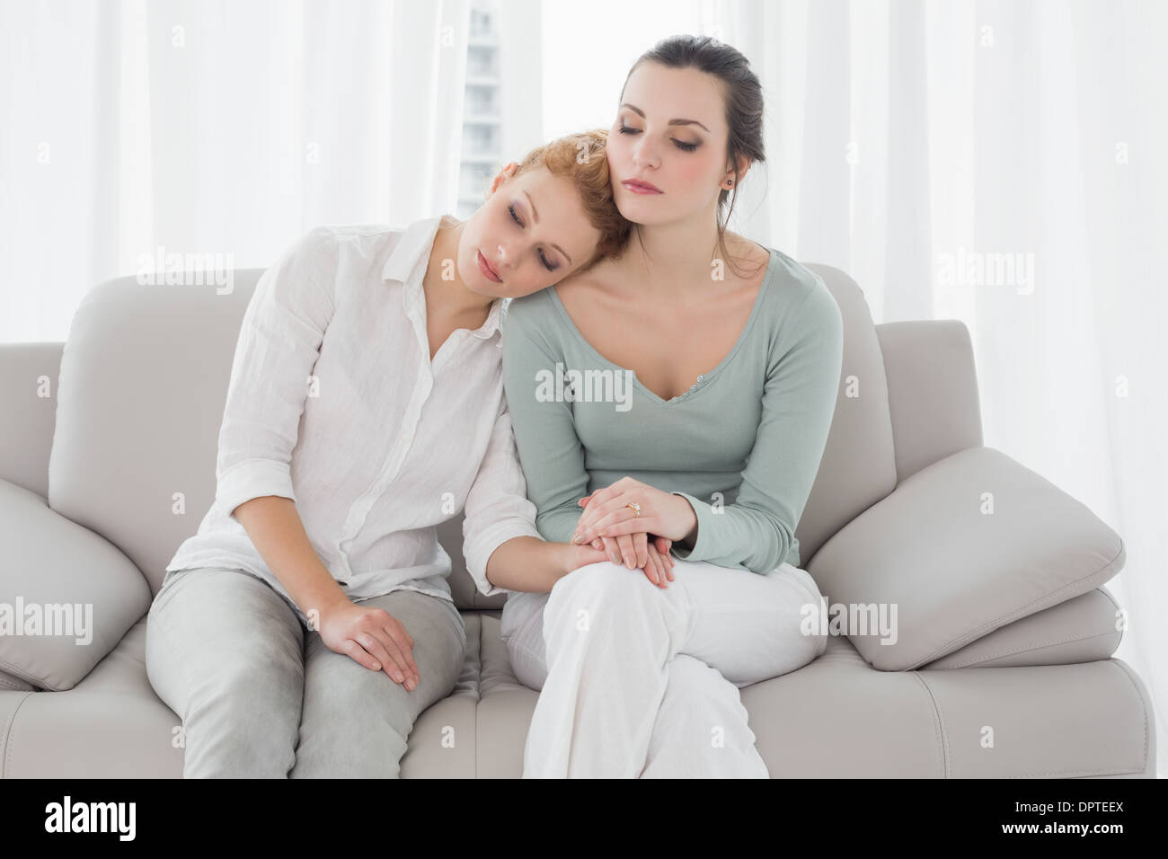Young woman consoling female friend on sofa Stock Photo - Alamy