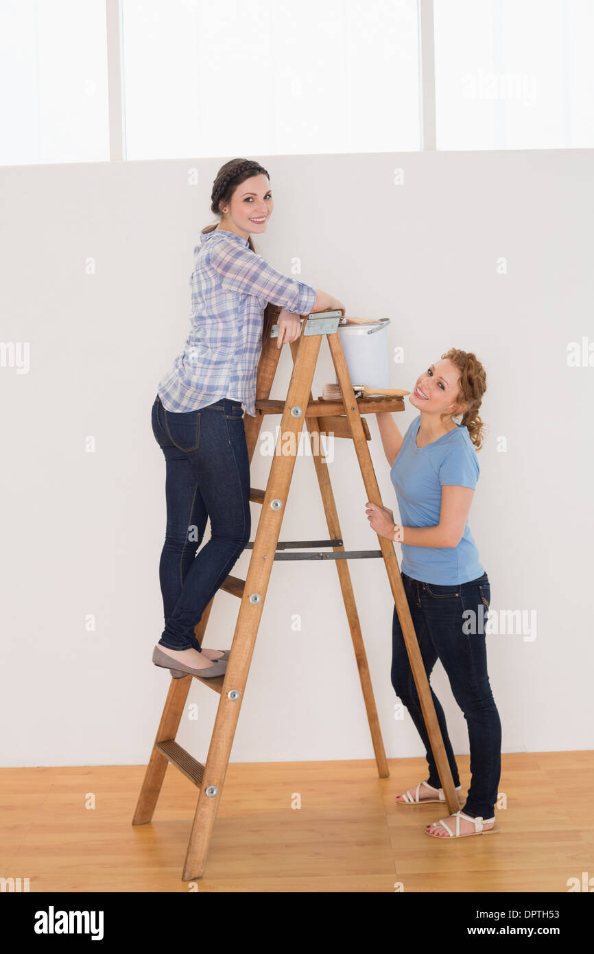 Female friends with a ladder in a new house Stock Photo - Alamy