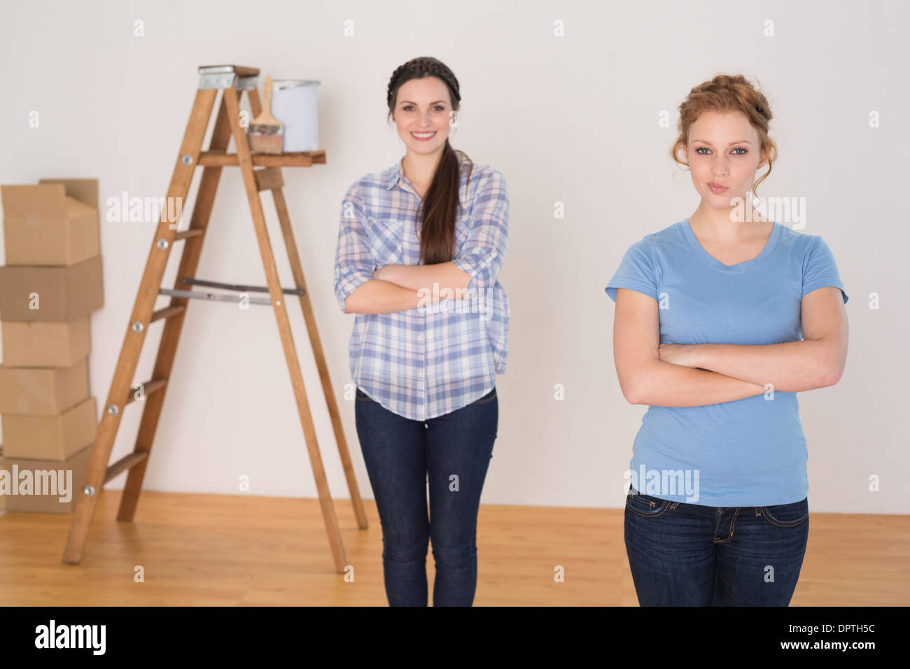 Friends standing with arms crossed in a new house Stock Photo - Alamy