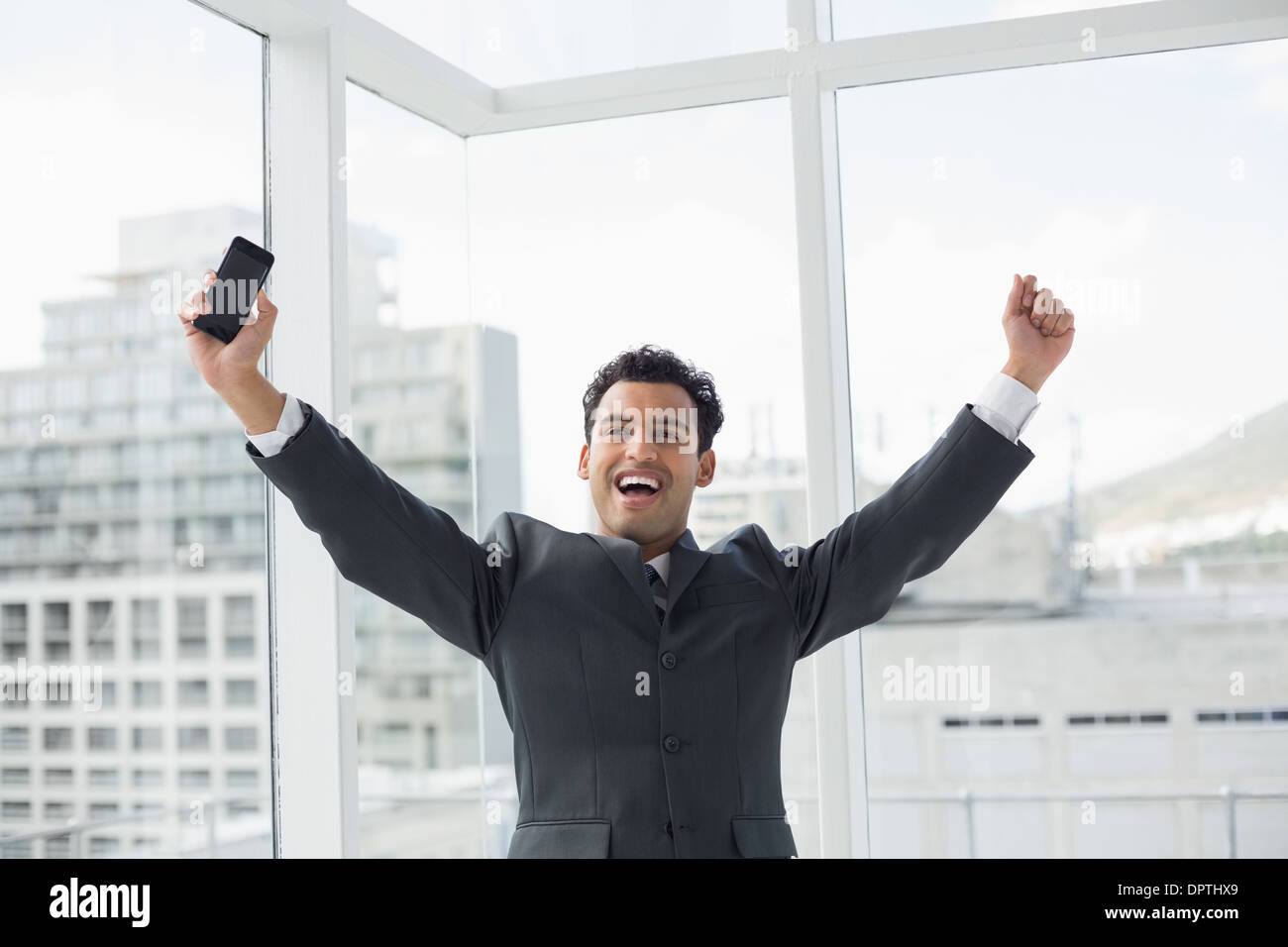 Elegant young businessman cheering in office Stock Photo - Alamy