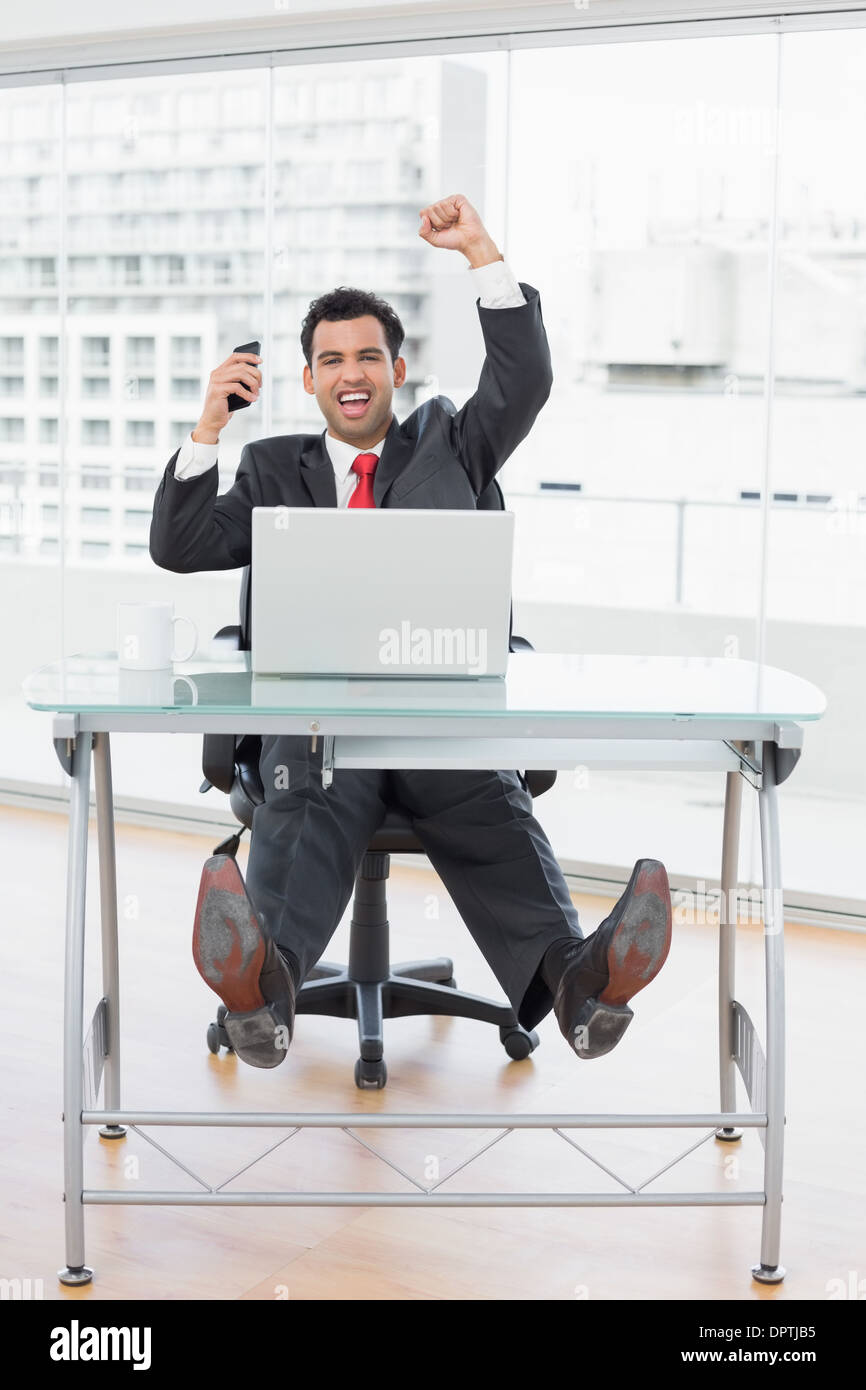 Businessman cheering in front of laptop at office desk Stock Photo - Alamy