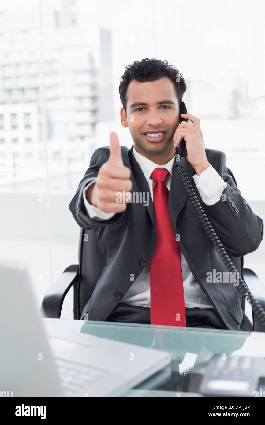 Businessman gesturing thumbs up while on call at office desk Stock ...