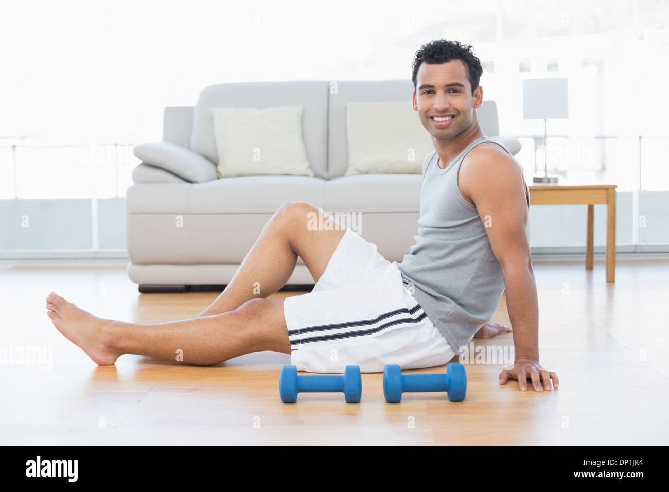 Relaxed man sitting on floor with dumbbells in the living room Stock ...