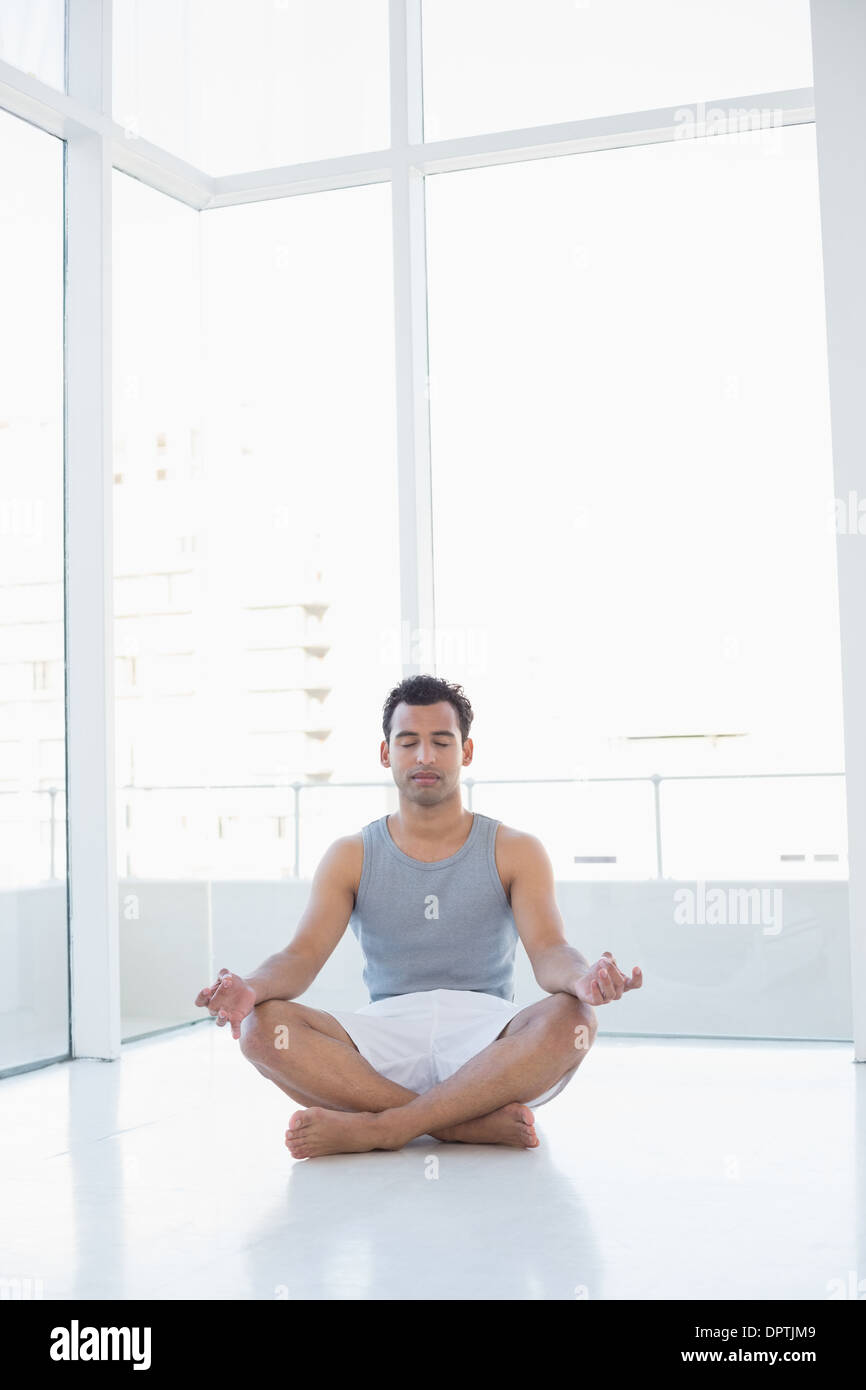 Full length of a young man sitting in lotus pose Stock Photo - Alamy