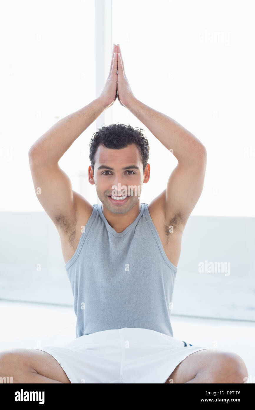 Smiling young man sitting with joined hands over head Stock Photo - Alamy