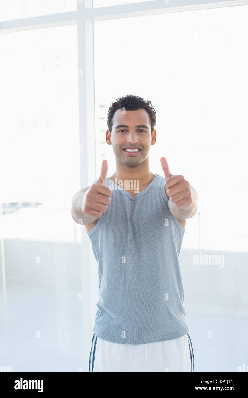 Fit young man gesturing thumbs up in fitness studio Stock Photo - Alamy