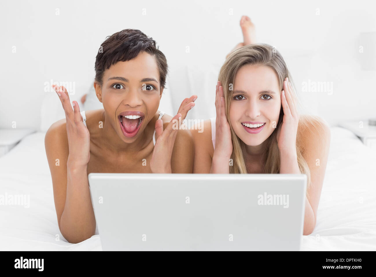 Shocked young female friends with laptop in bed Stock Photo - Alamy