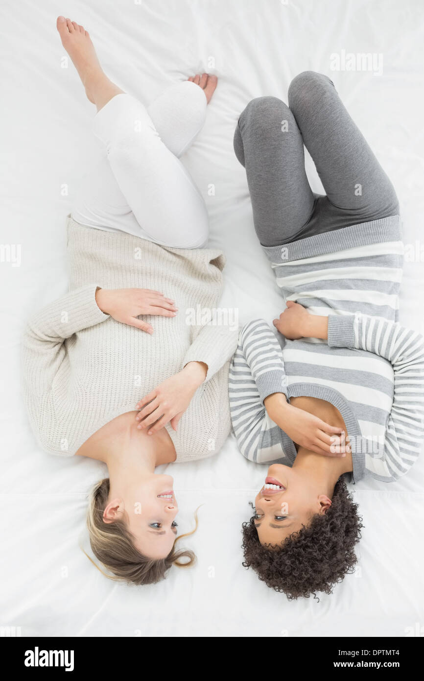 Cheerful young female friends lying in bed Stock Photo - Alamy