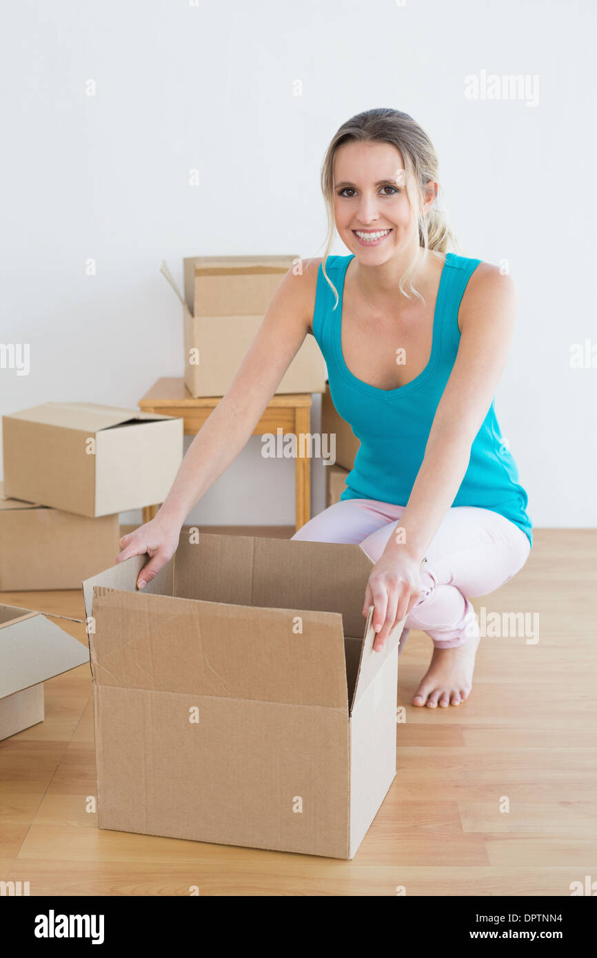Happy young woman unwrapping boxes in new house Stock Photo - Alamy
