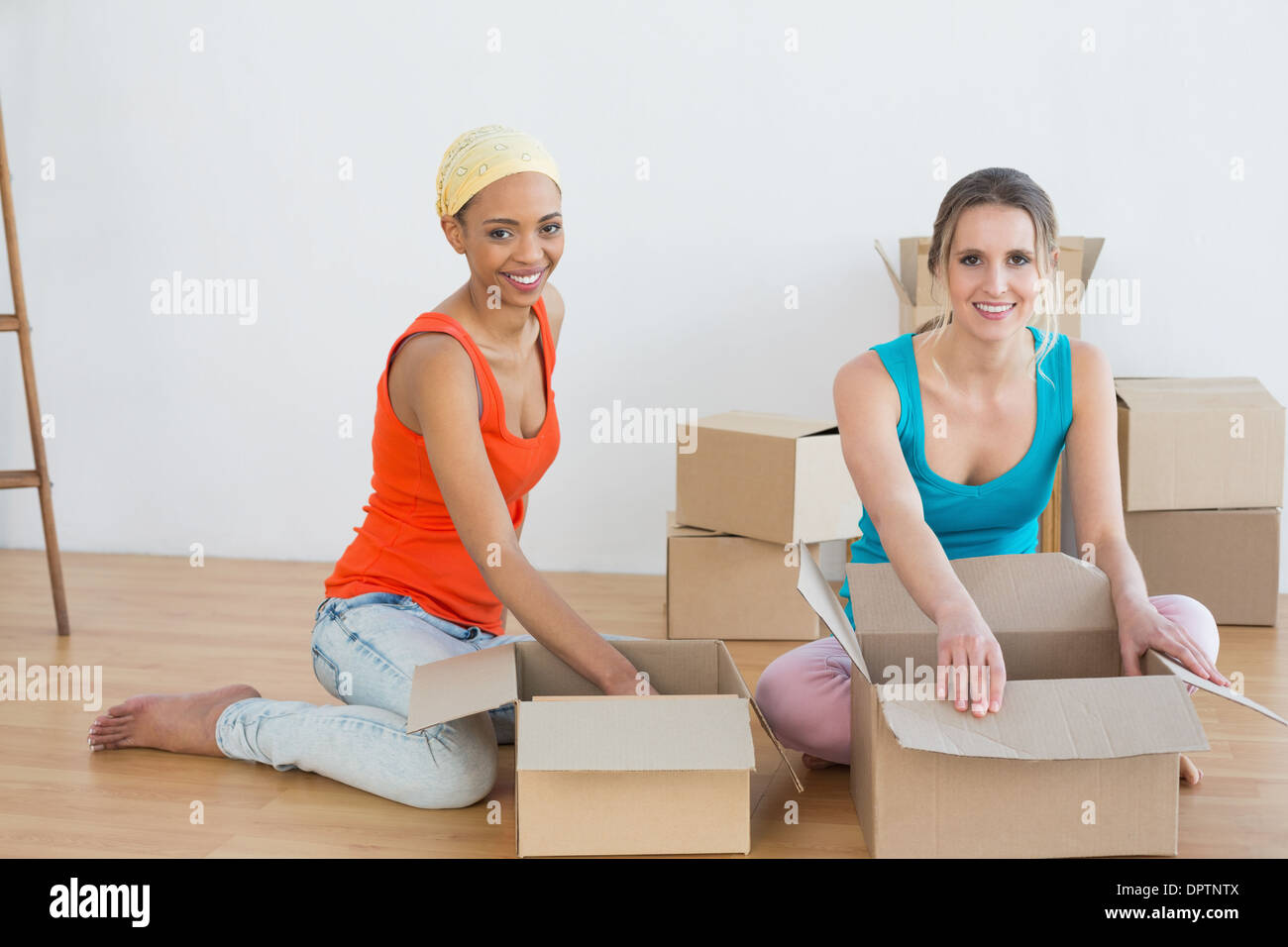 Happy friends unwrapping boxes in a new house Stock Photo - Alamy