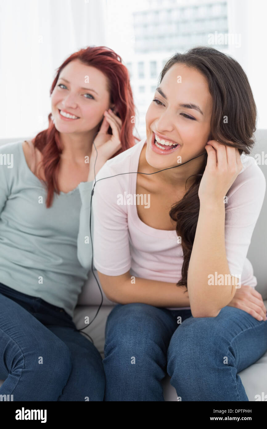 Friends listening music through earphones together at home Stock Photo ...